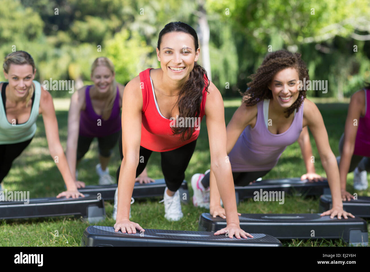 Fitness group using steps in park Stock Photo - Alamy