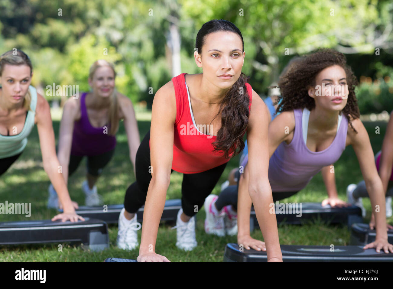 Fitness group using steps in park Stock Photo - Alamy