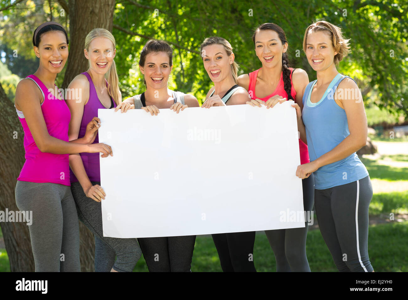 Fitness group holding poster in park Stock Photo - Alamy