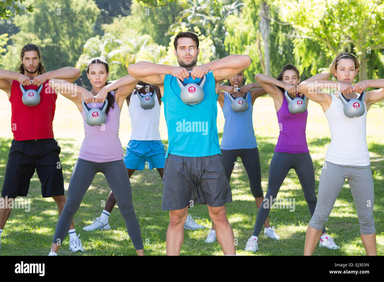 Fitness group working out in park with kettle bells Stock Photo - Alamy
