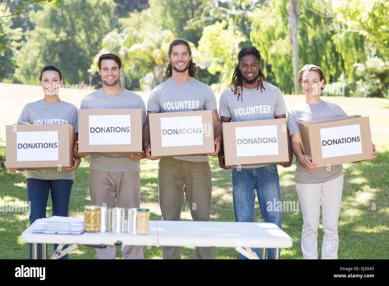 Happy volunteers with donation boxes in park Stock Photo - Alamy