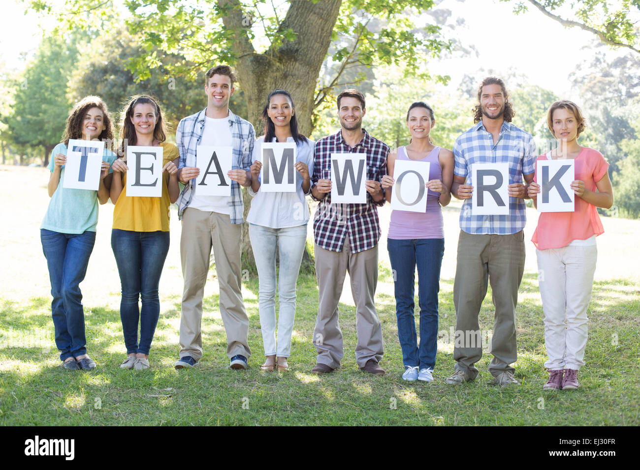 Friends holding teamwork signs in the park Stock Photo - Alamy