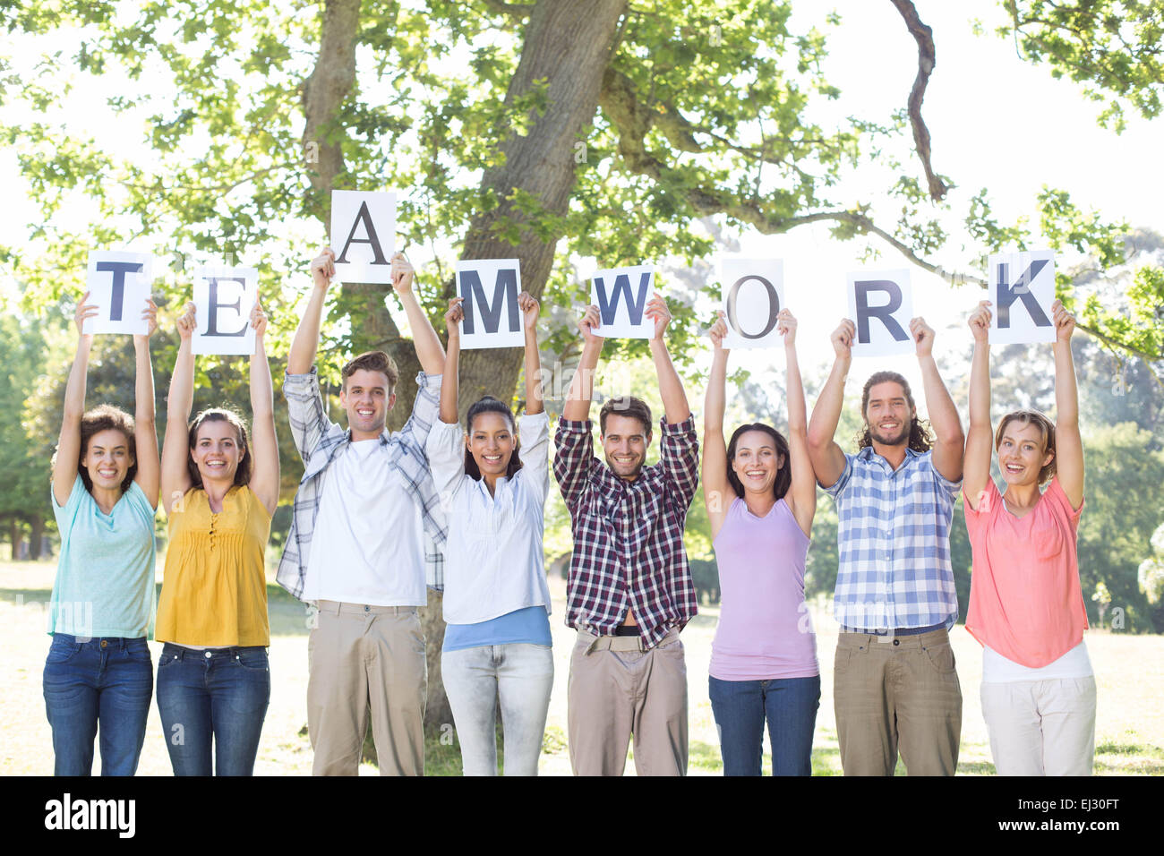 Friends holding teamwork signs in the park Stock Photo - Alamy