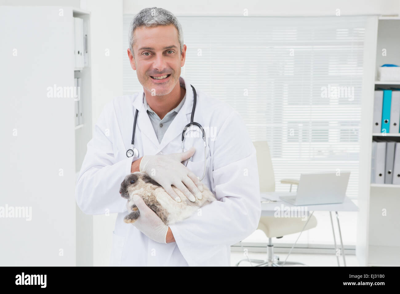 Smiling vet with a rabbit in his arms Stock Photo - Alamy
