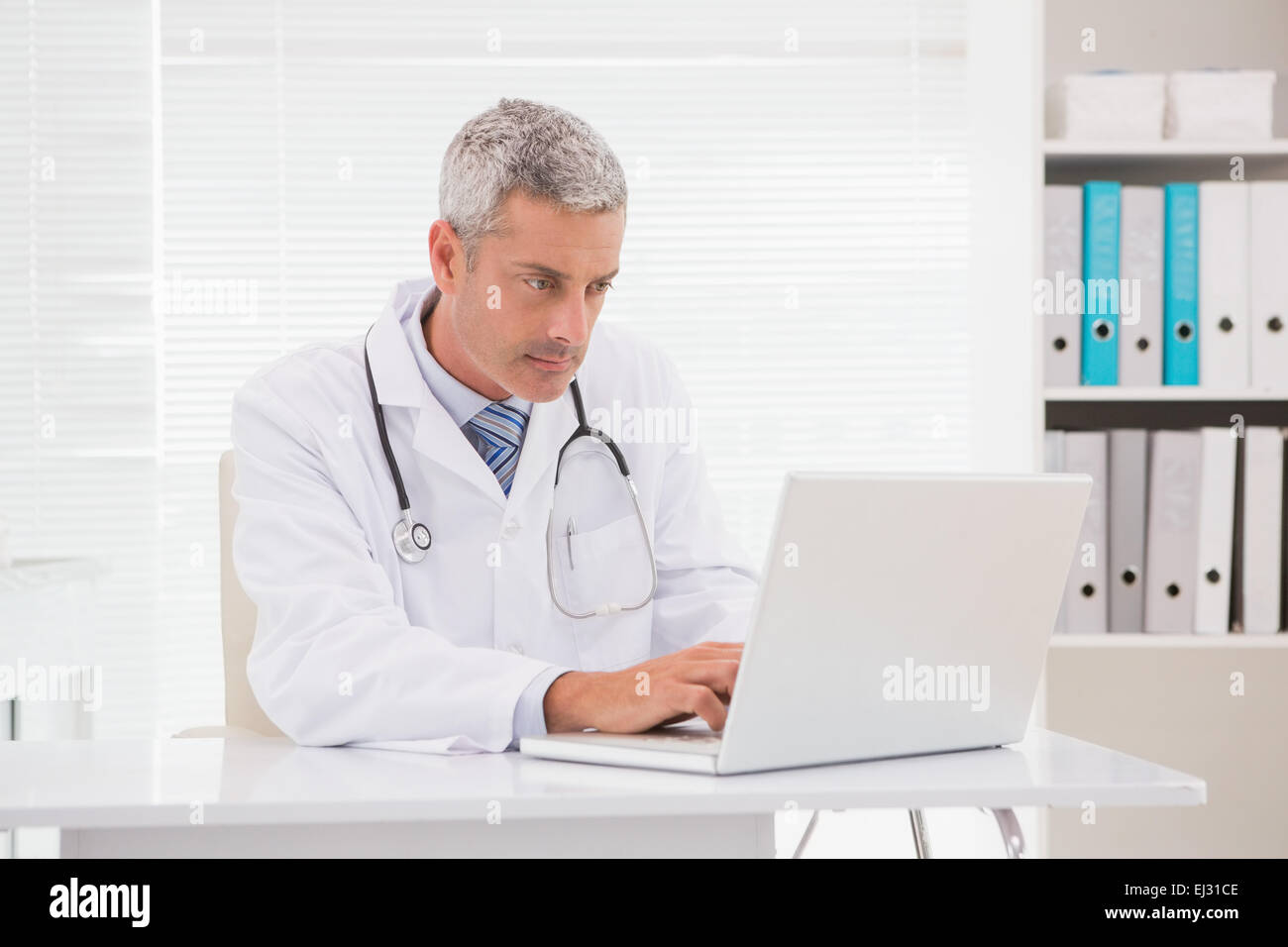Serious doctor using laptop Stock Photo - Alamy
