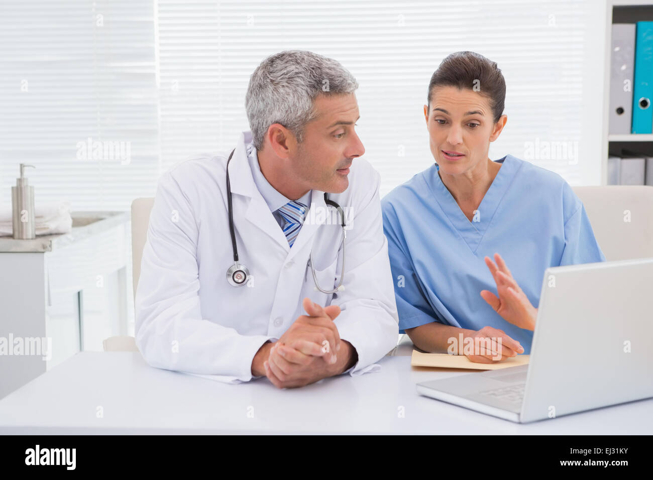 Doctors looking at laptop Stock Photo - Alamy