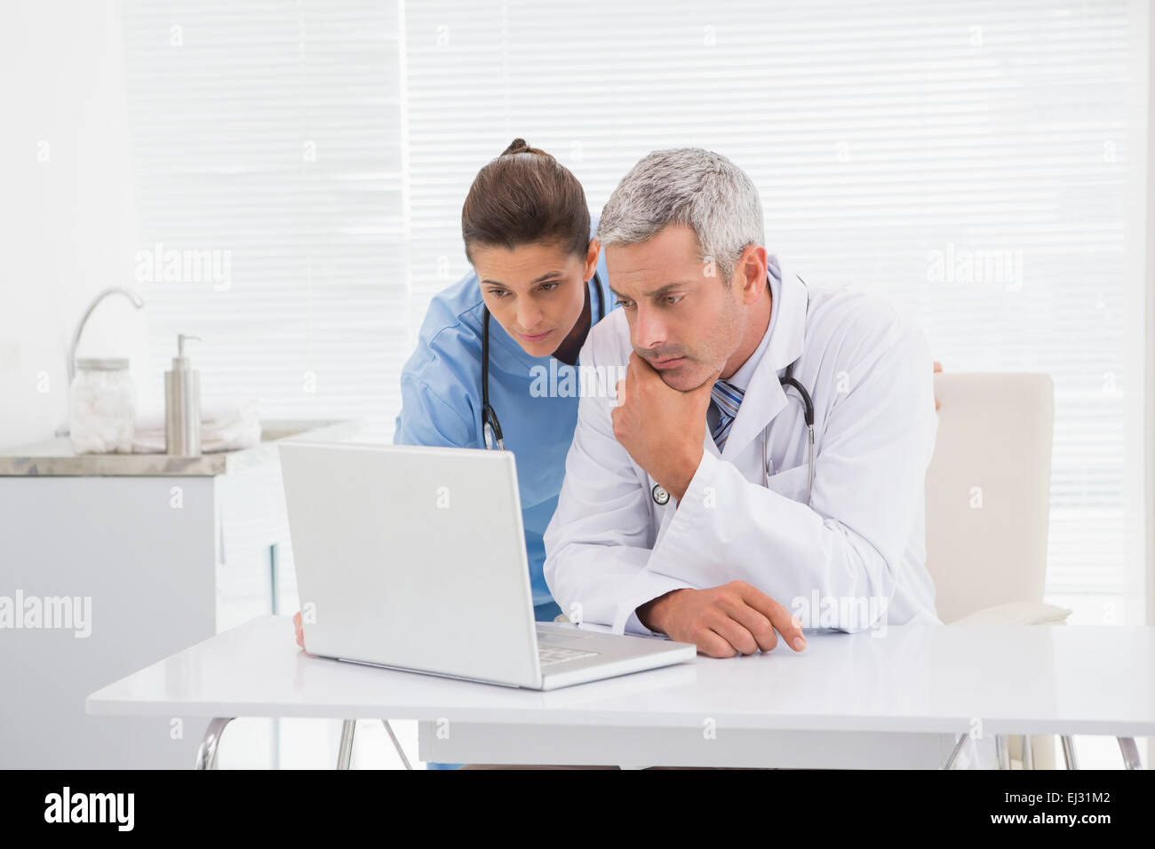 Doctors looking at laptop Stock Photo - Alamy
