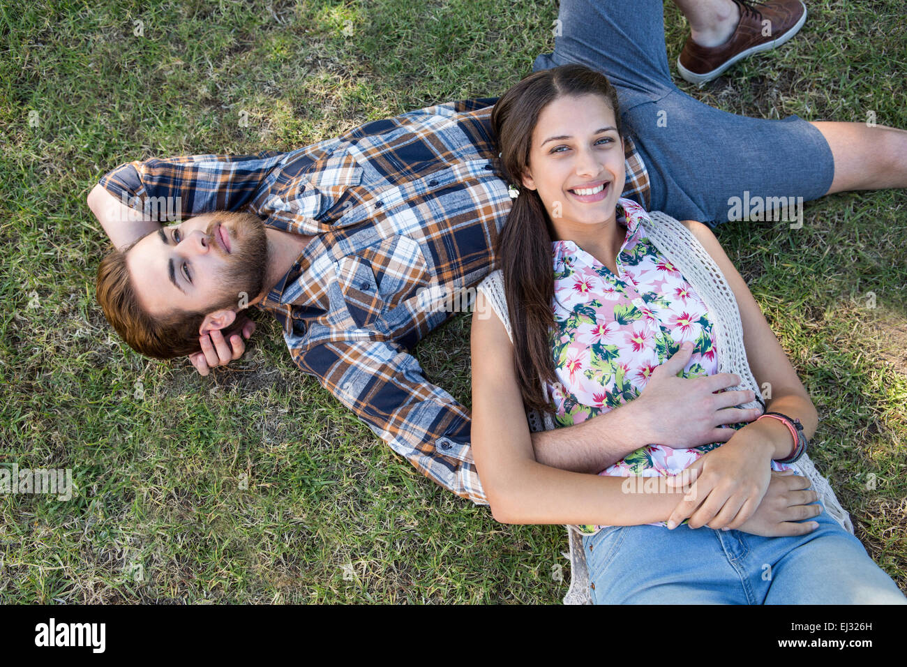 Young couple relaxing in the park smiling at camera Stock Photo - Alamy