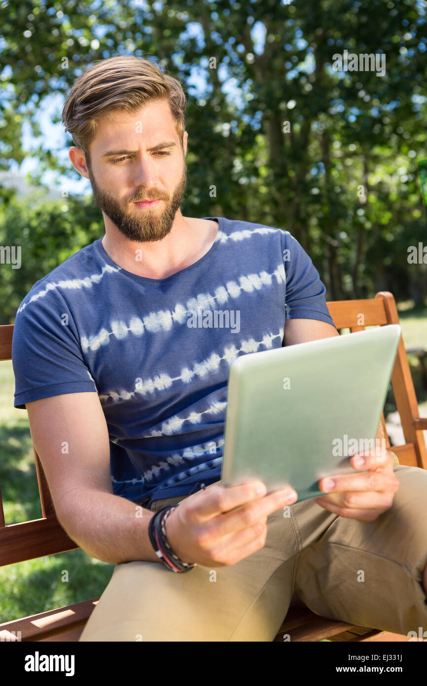 Young man using tablet on park bench Stock Photo - Alamy