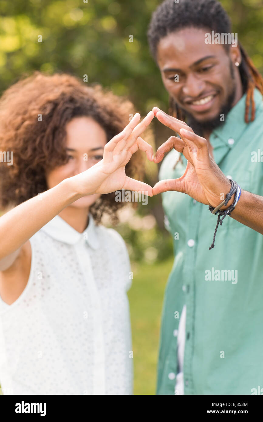 Cute couple in the park making heart shape Stock Photo - Alamy