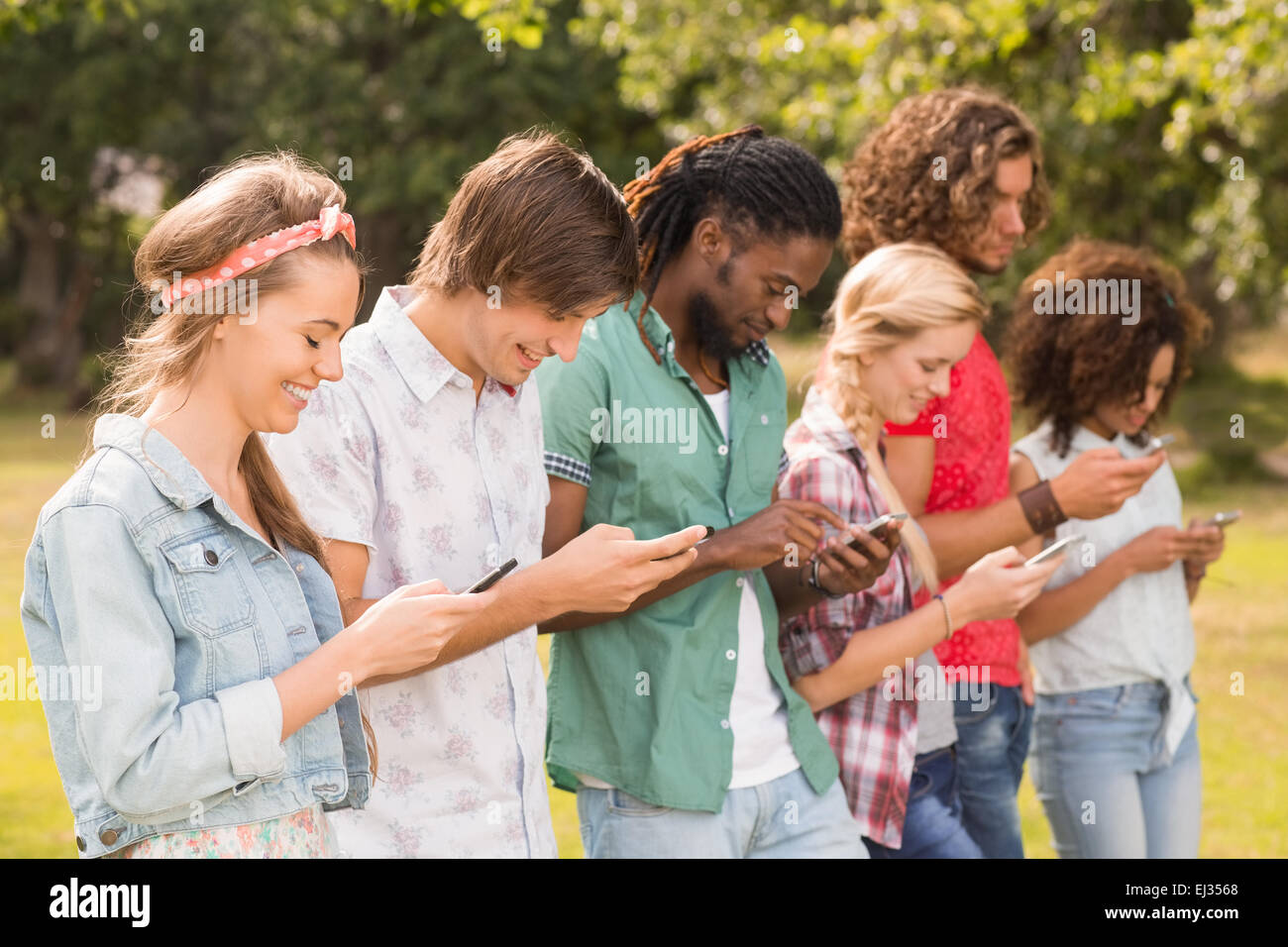 Happy friends in the park using their phones Stock Photo - Alamy