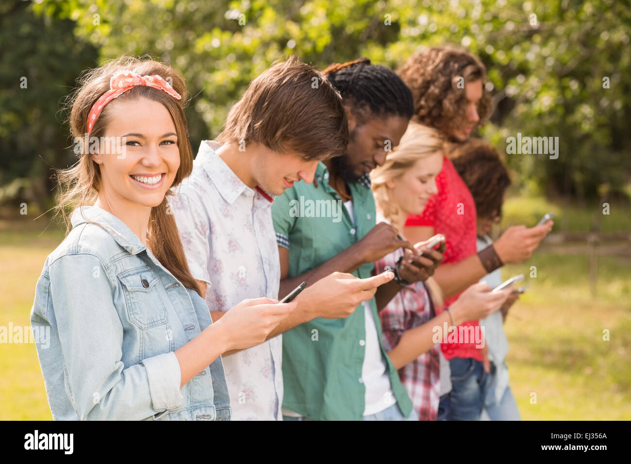 Happy friends in the park using their phones Stock Photo - Alamy