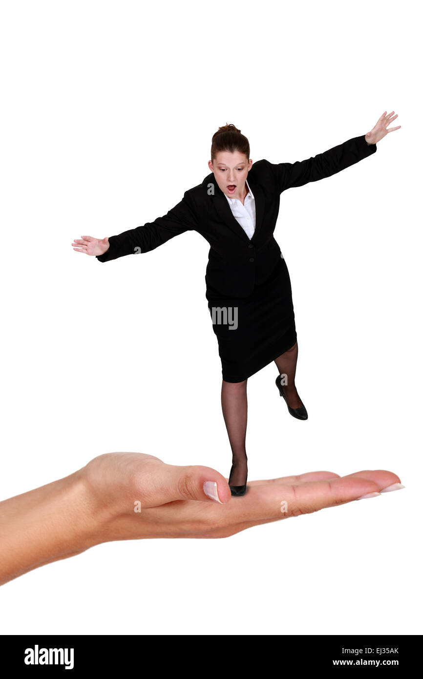 Businesswoman balancing on giant hand Stock Photo - Alamy