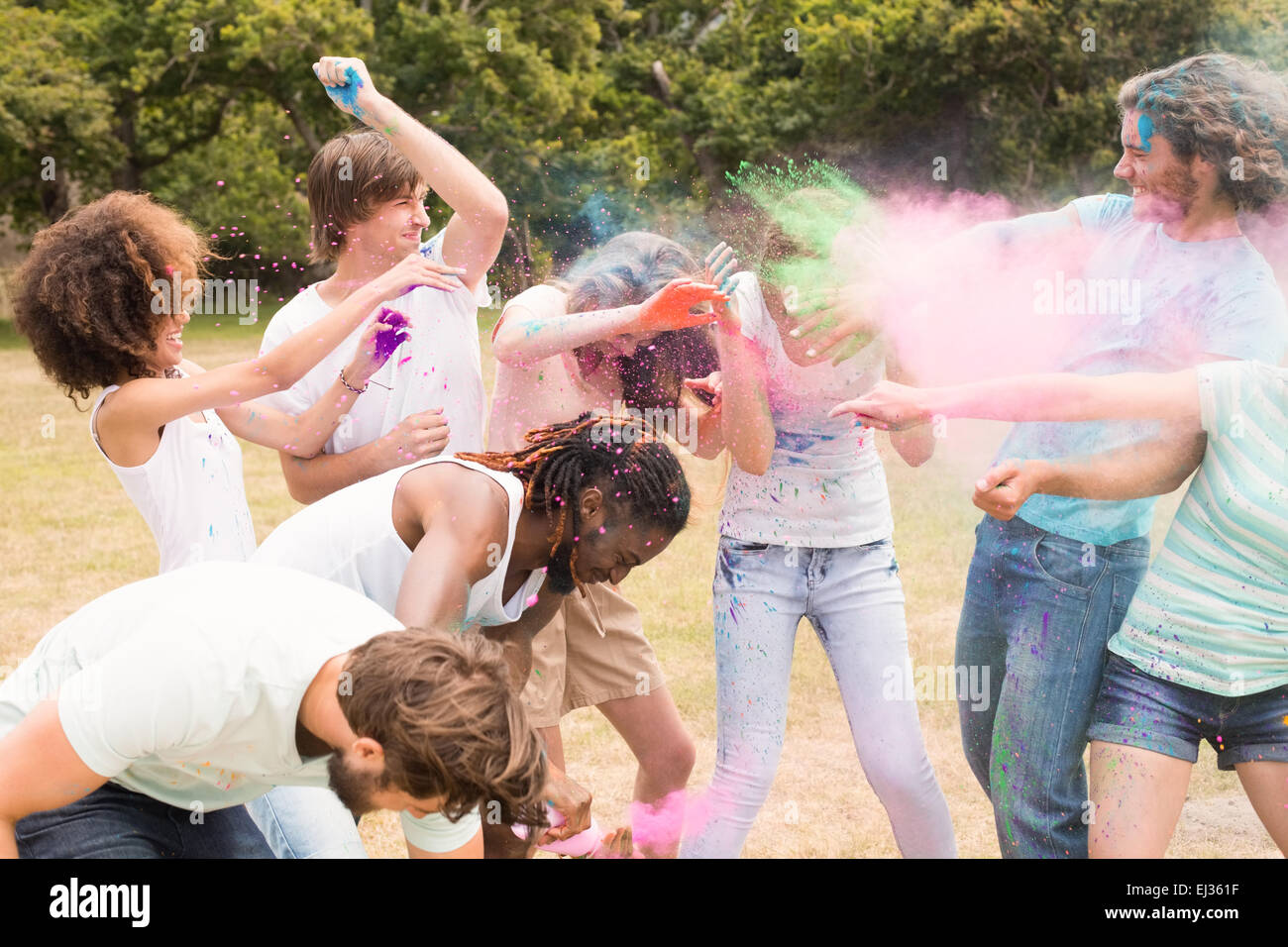 Happy friends throwing powder paint Stock Photo - Alamy