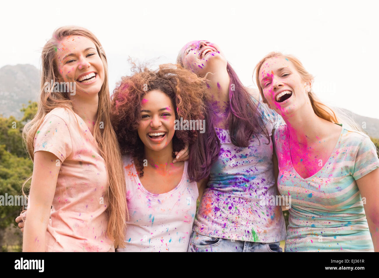 Happy friends throwing powder paint Stock Photo - Alamy