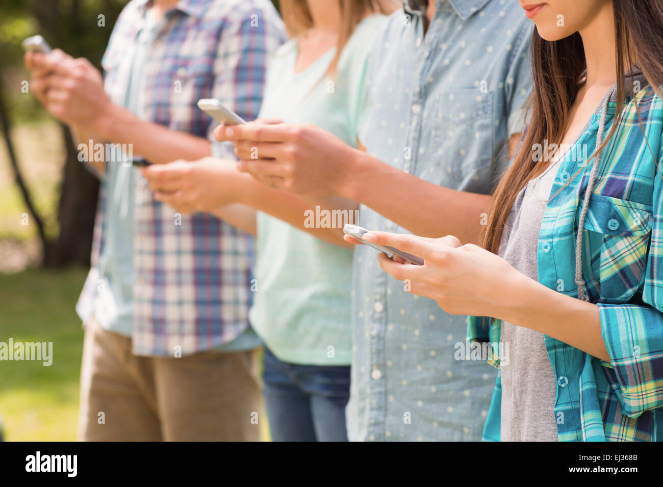 Happy friends in the park using their phones Stock Photo - Alamy
