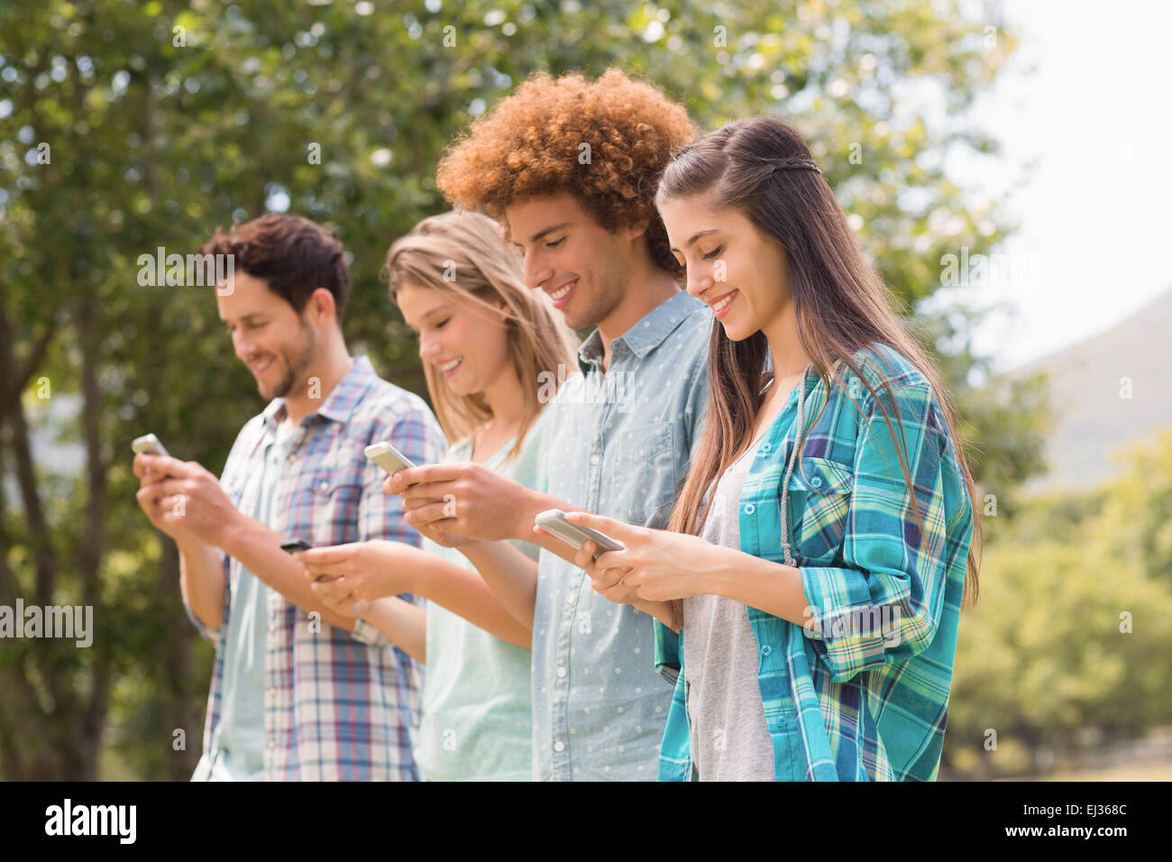 Happy friends in the park using their phones Stock Photo - Alamy