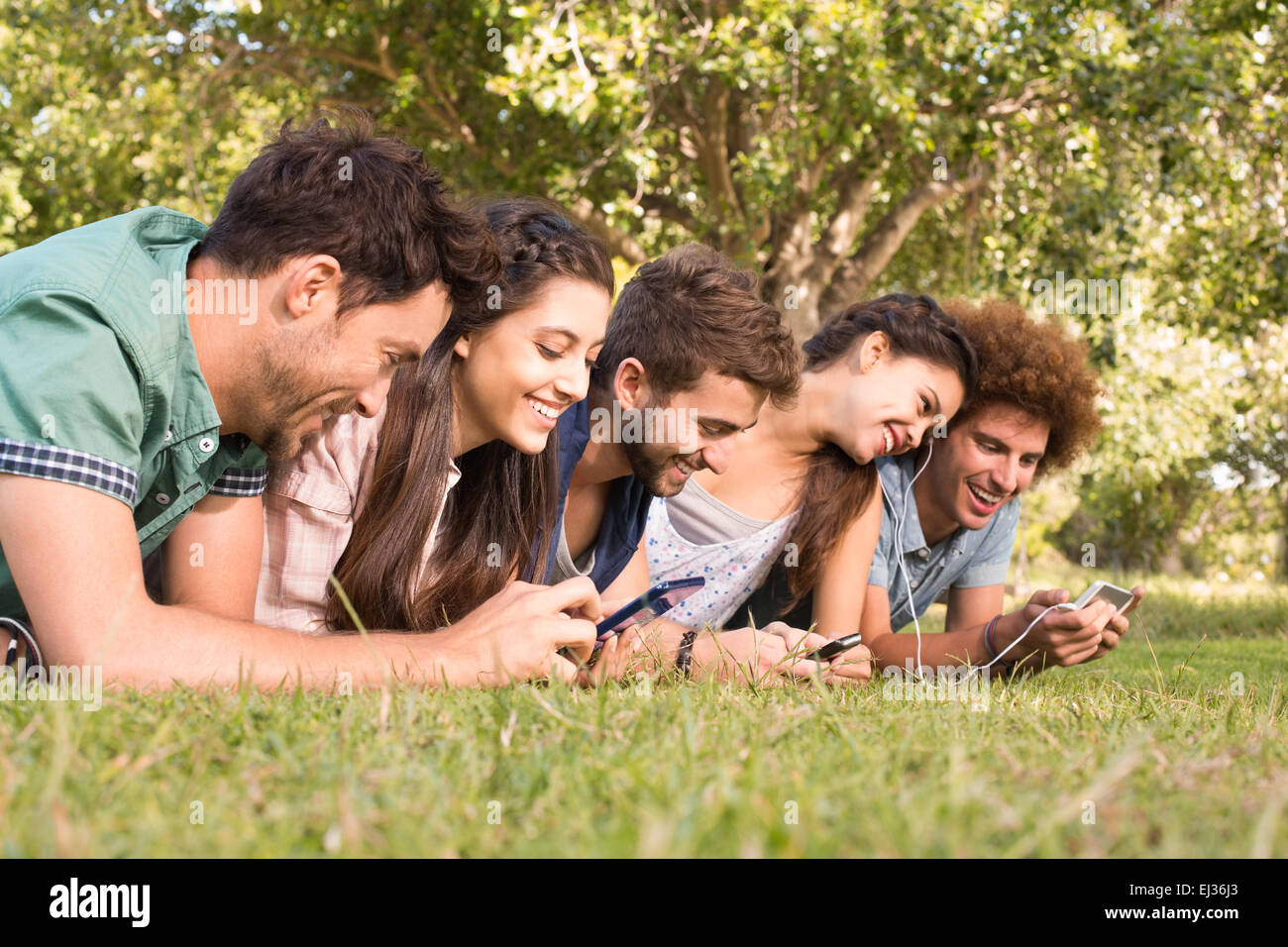 Happy friends in the park using their phones Stock Photo - Alamy