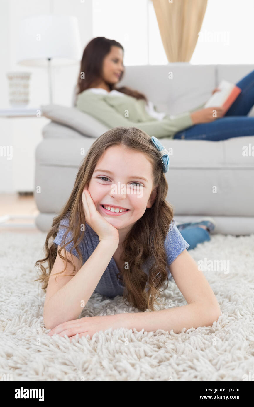 Happy girl lying on rug while mother relaxing at home Stock Photo - Alamy