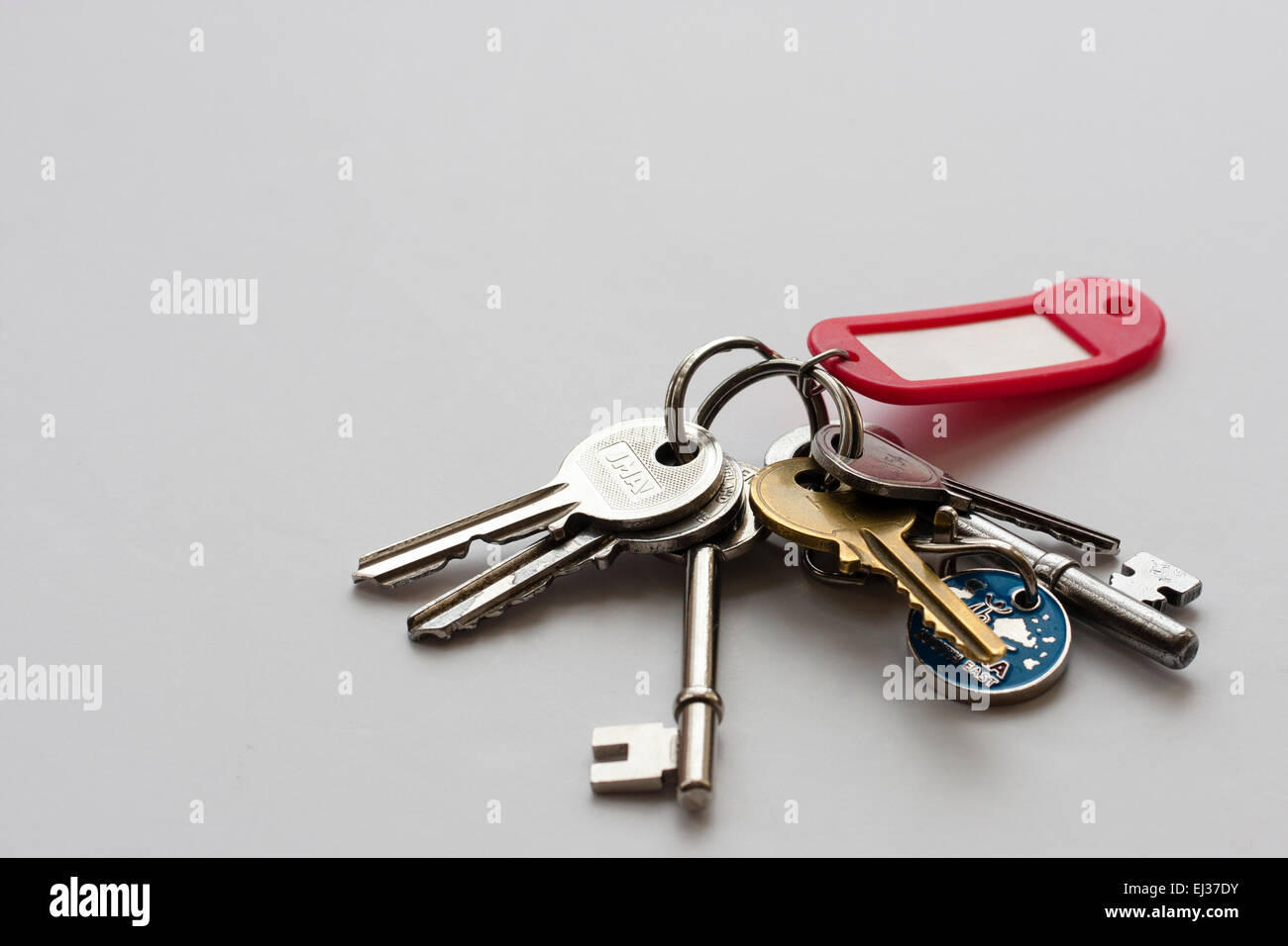 Bunch of keys on key ring with red tag laying on plain white background ...