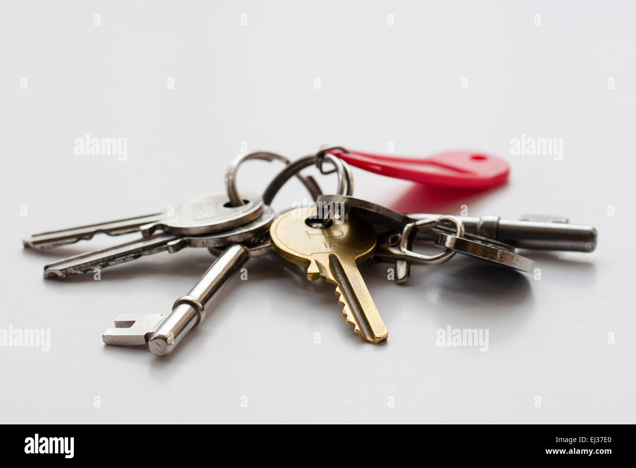 Bunch of keys on key ring with red tag laying on plain white background ...