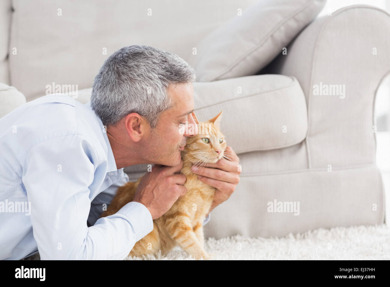 Man kissing cat by sofa at home Stock Photo - Alamy