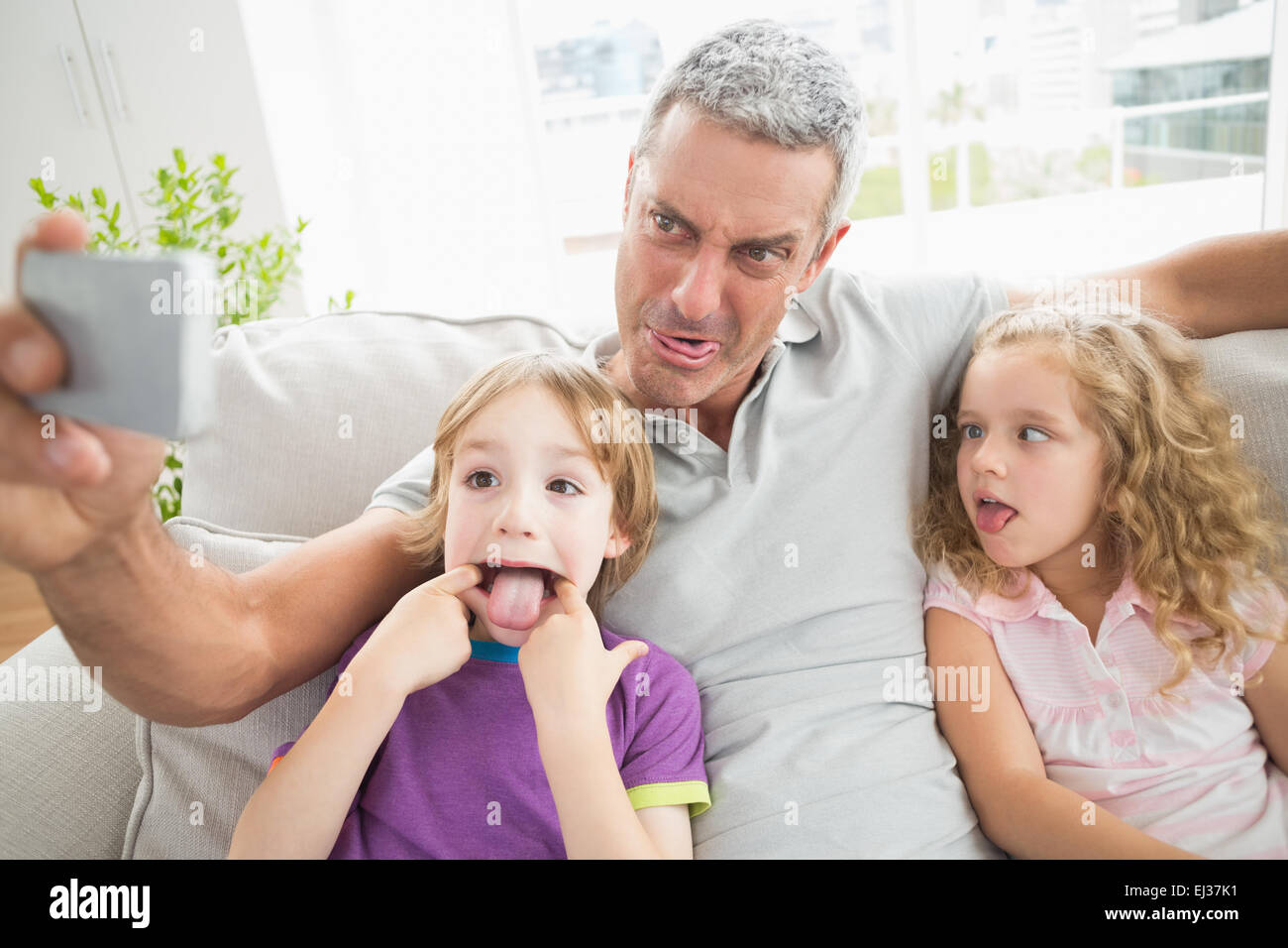 Father making face while taking selfie with children Stock Photo - Alamy