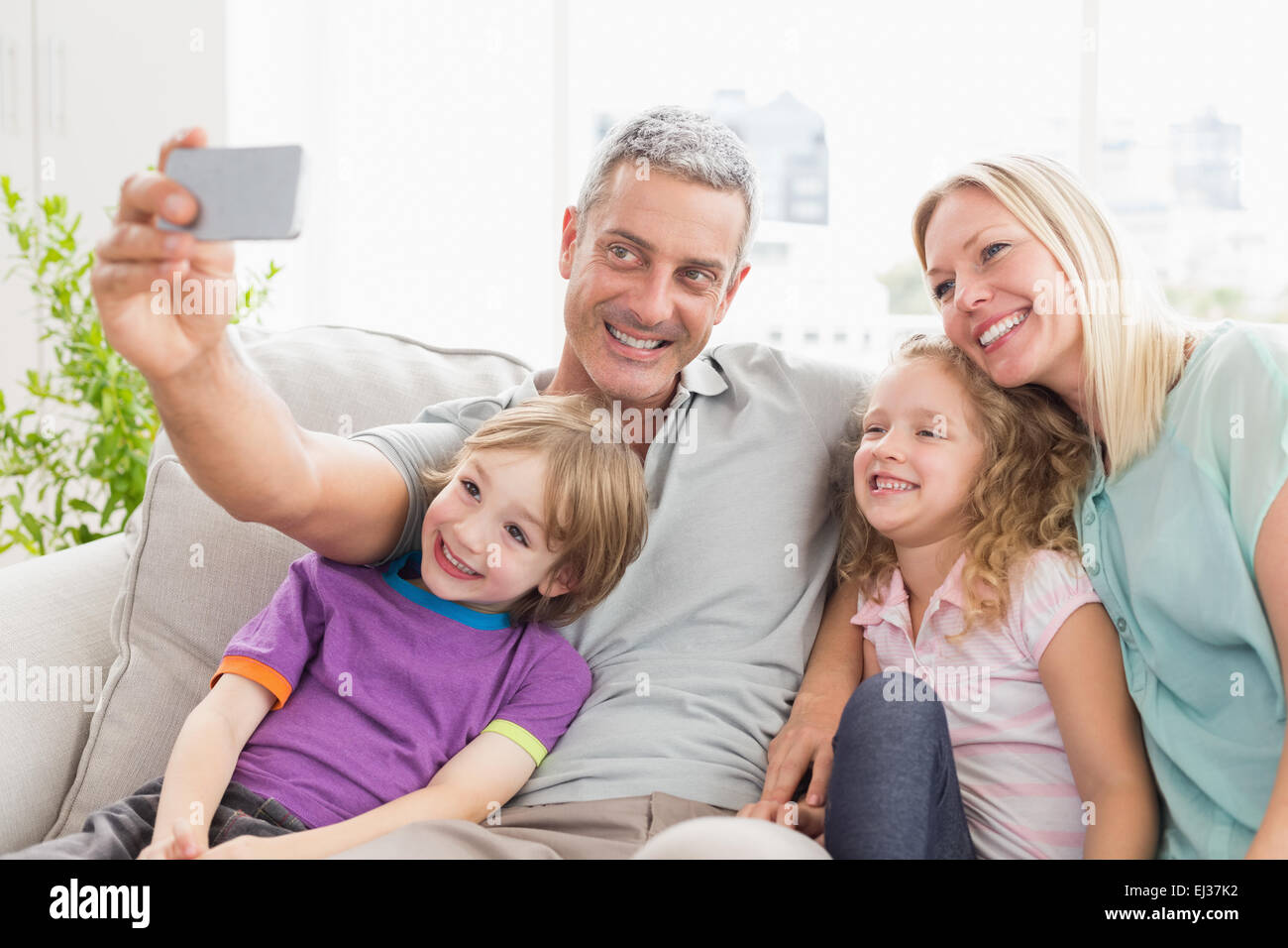 Man taking selfie with family on sofa Stock Photo - Alamy