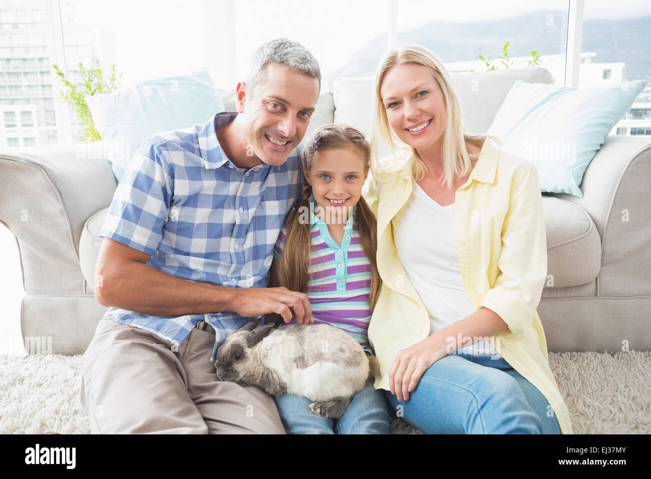 Happy parents and daughter with rabbit in living room Stock Photo - Alamy