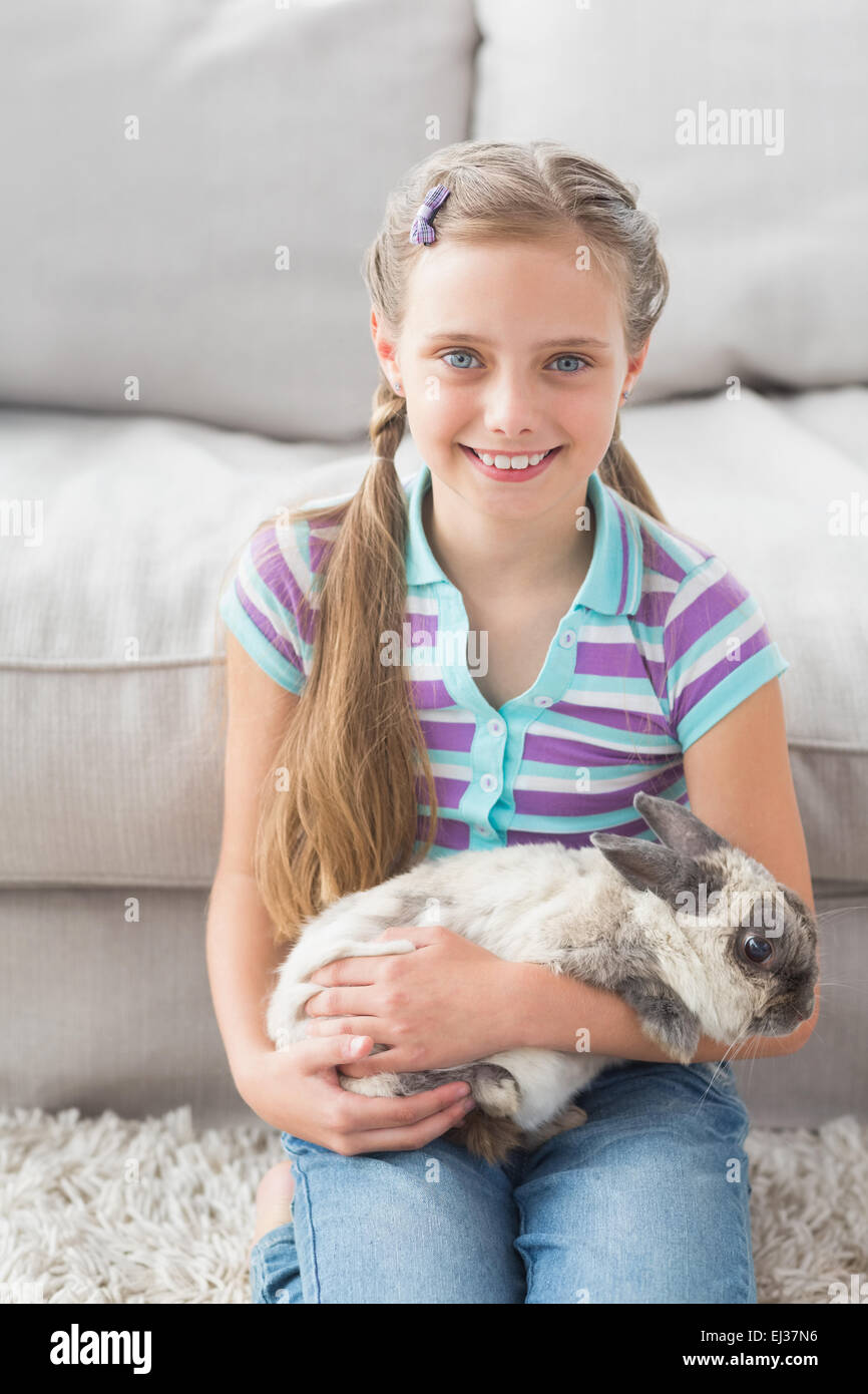 Cute girl holding rabbit in living area Stock Photo - Alamy