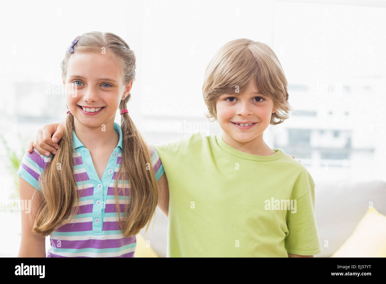 Happy siblings standing arm around at home Stock Photo - Alamy