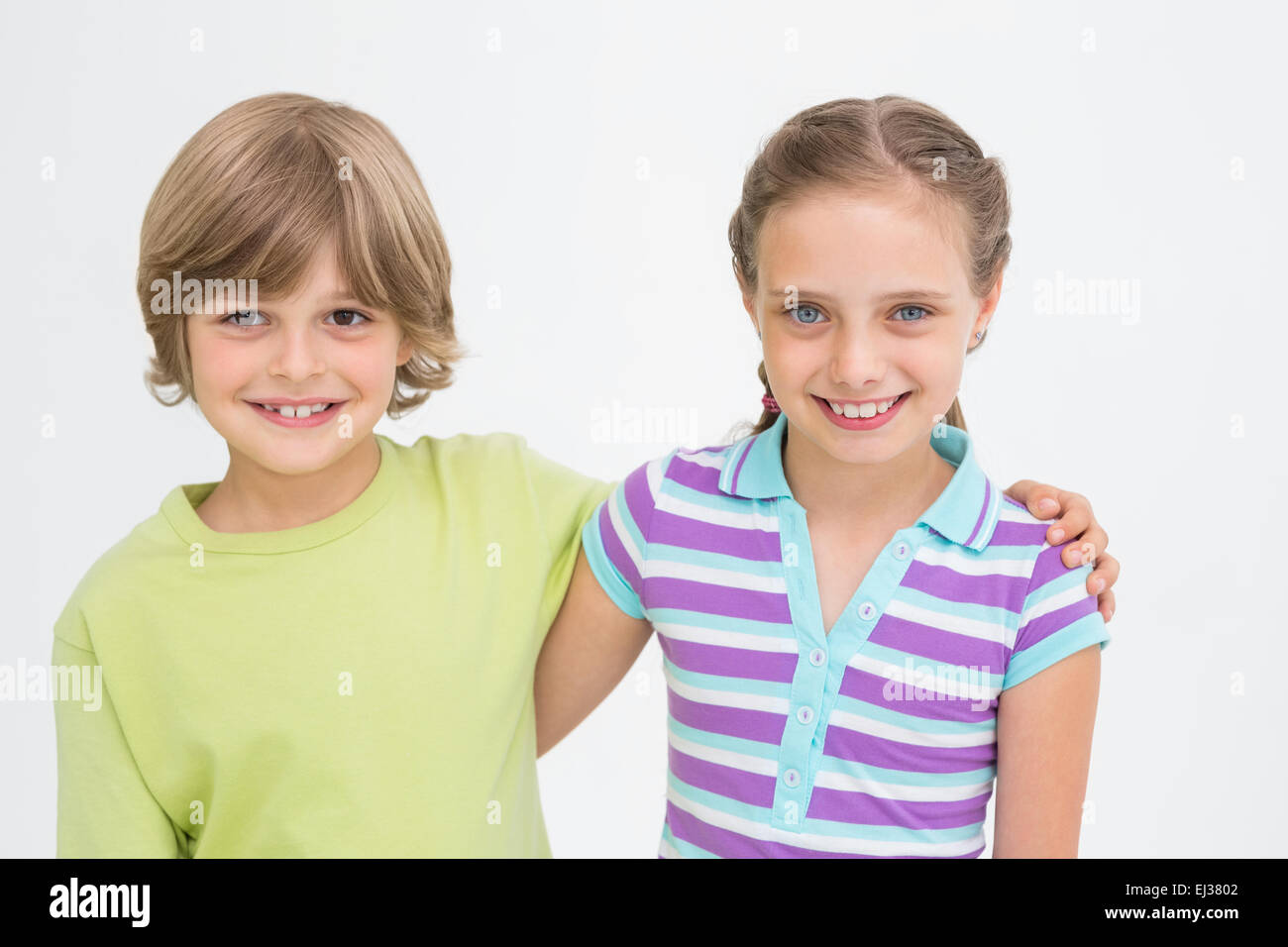 Cute siblings standing arm around on white background Stock Photo - Alamy