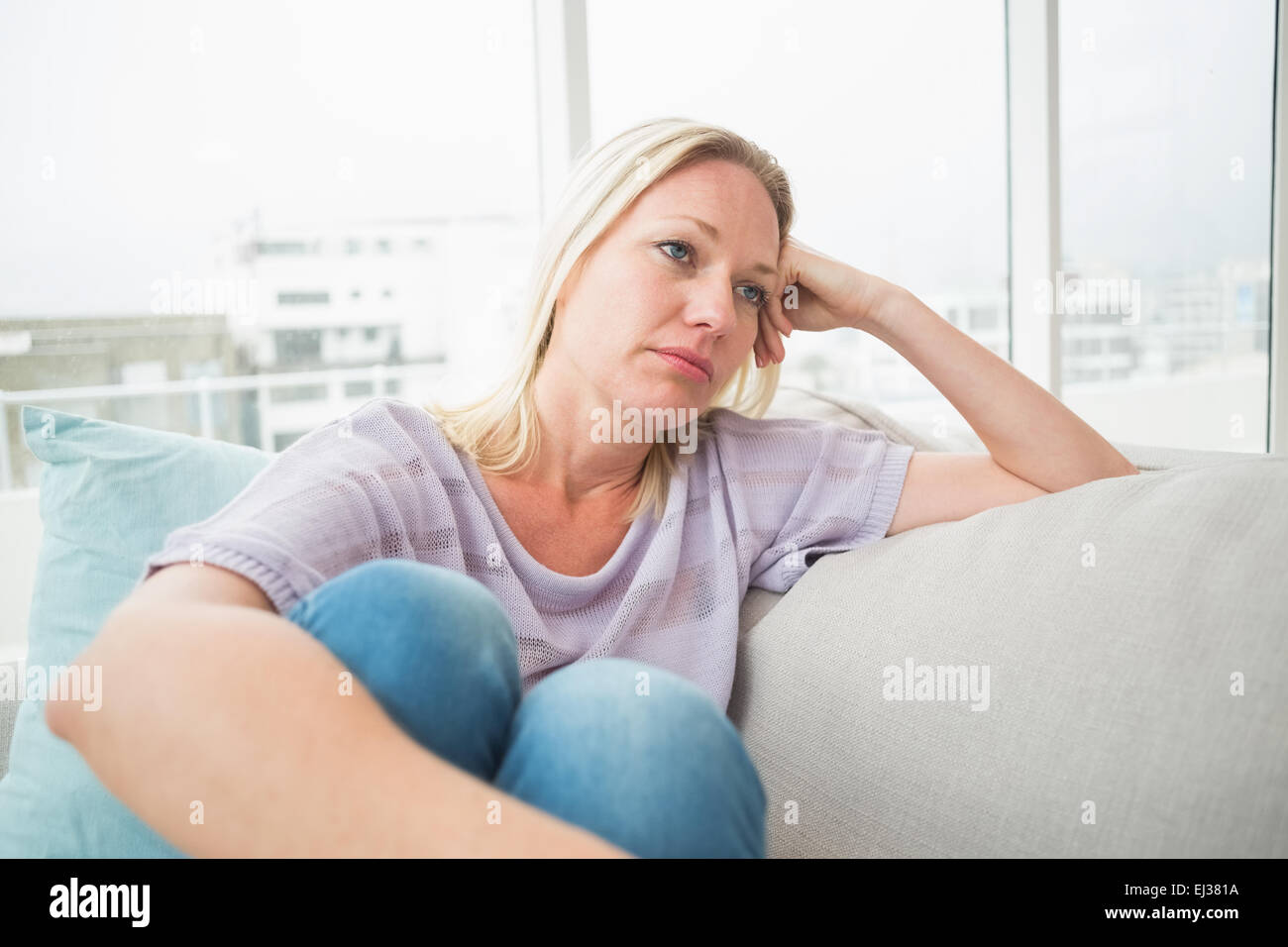 Sad woman sitting on sofa Stock Photo - Alamy