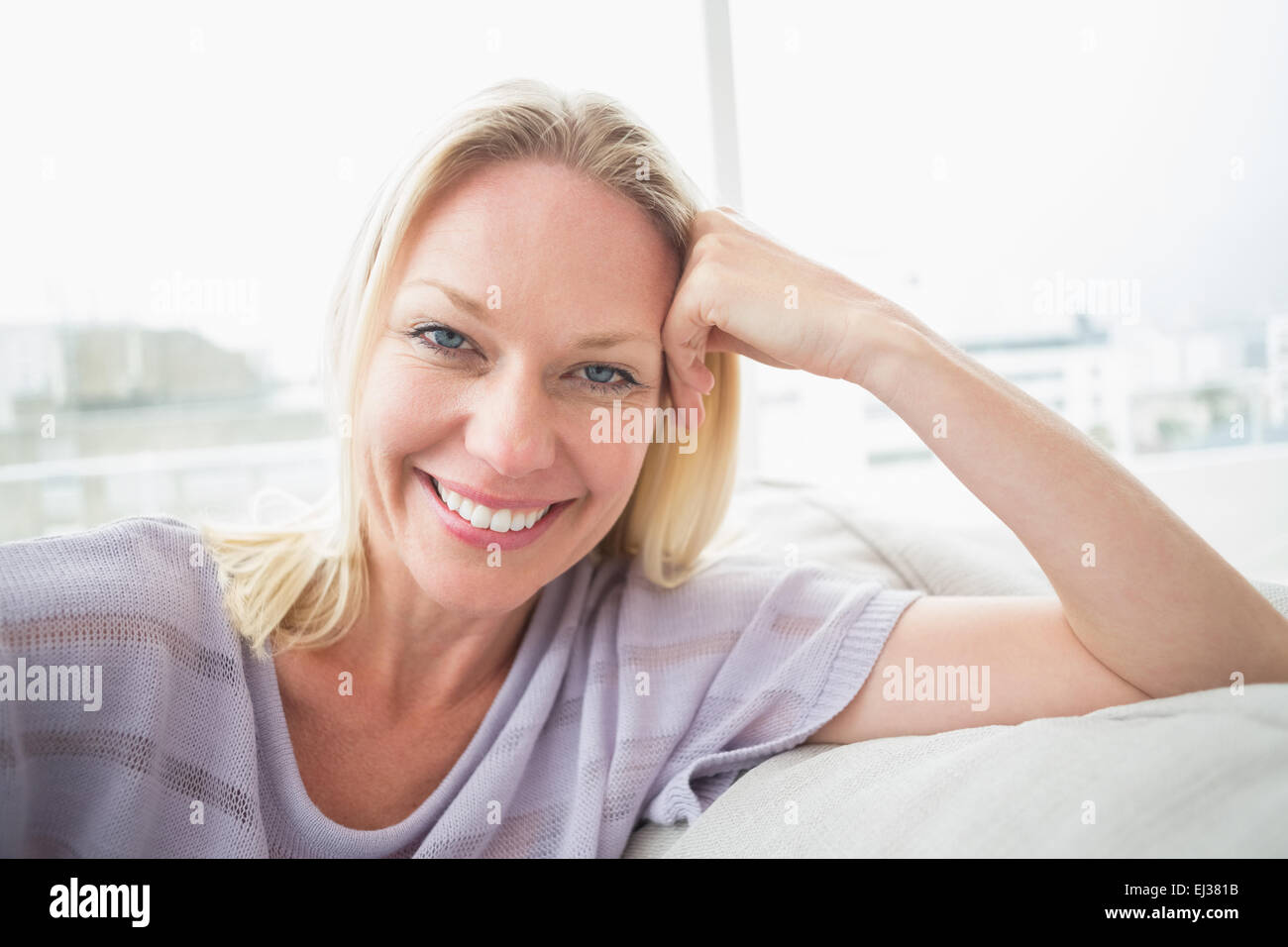 Portrait of smiling woman relaxing on sofa Stock Photo - Alamy