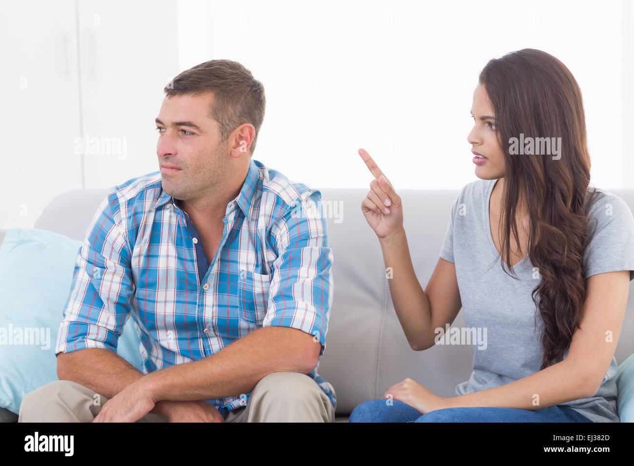 Woman arguing with man while sitting on sofa Stock Photo - Alamy