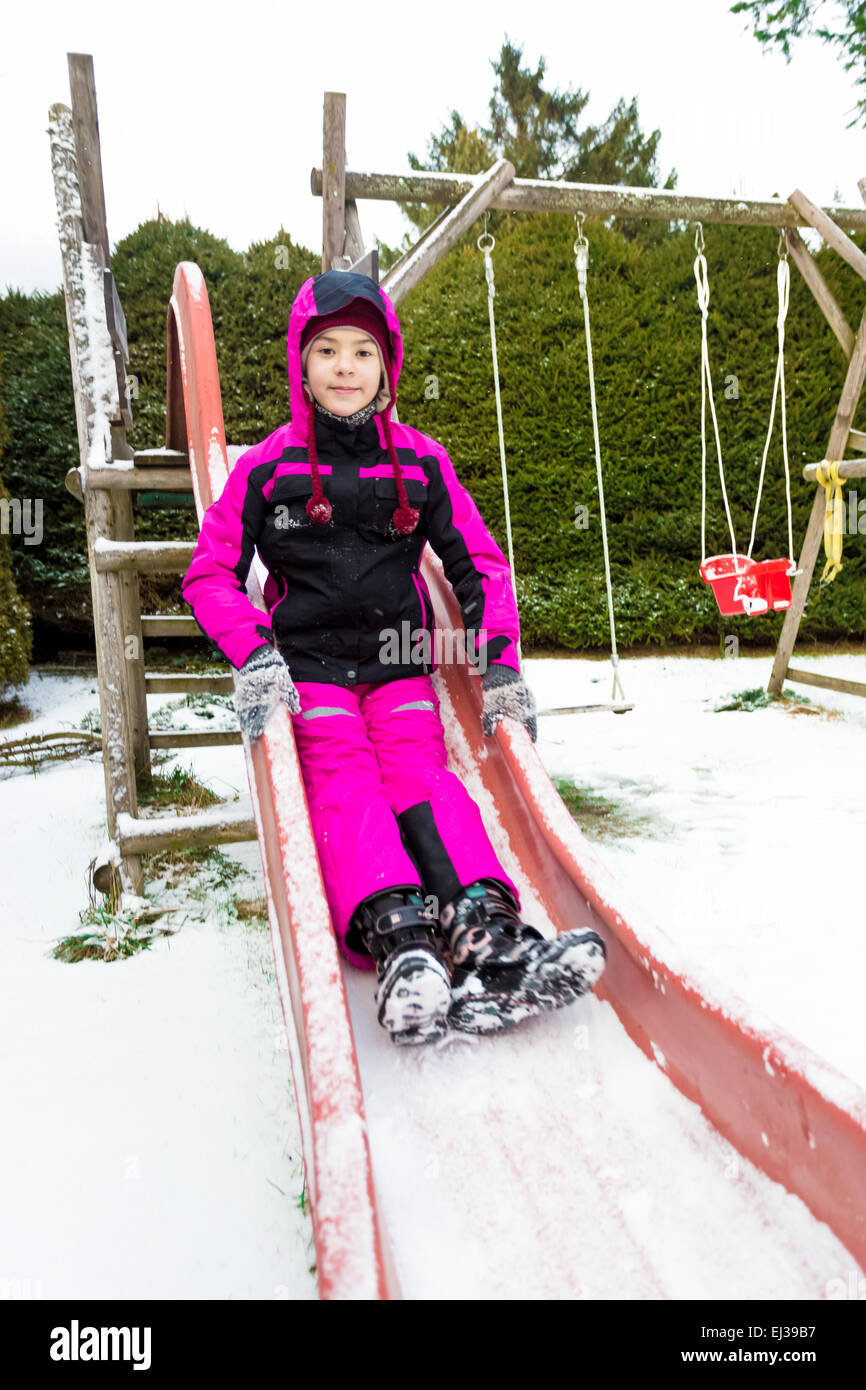 Happy smiling girl on slide at cold snowy day Stock Photo - Alamy