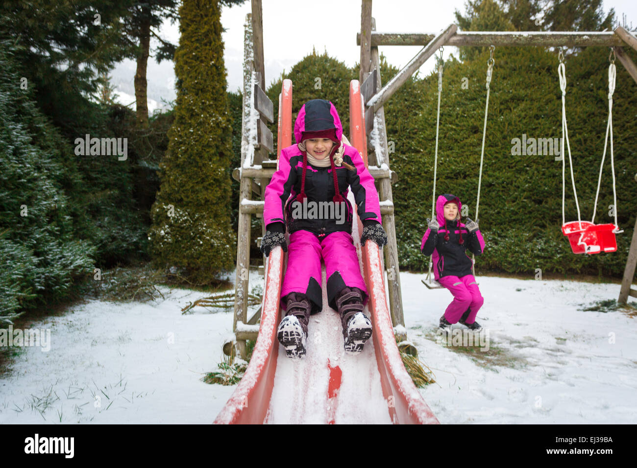 Two happy little girls having fun on playground at cold snowy day Stock ...