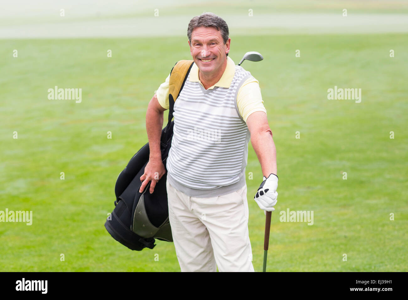Handsome golfer standing with golf bag Stock Photo - Alamy