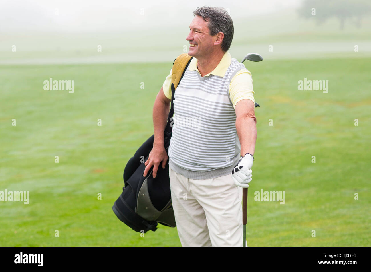Handsome golfer standing with golf bag Stock Photo - Alamy