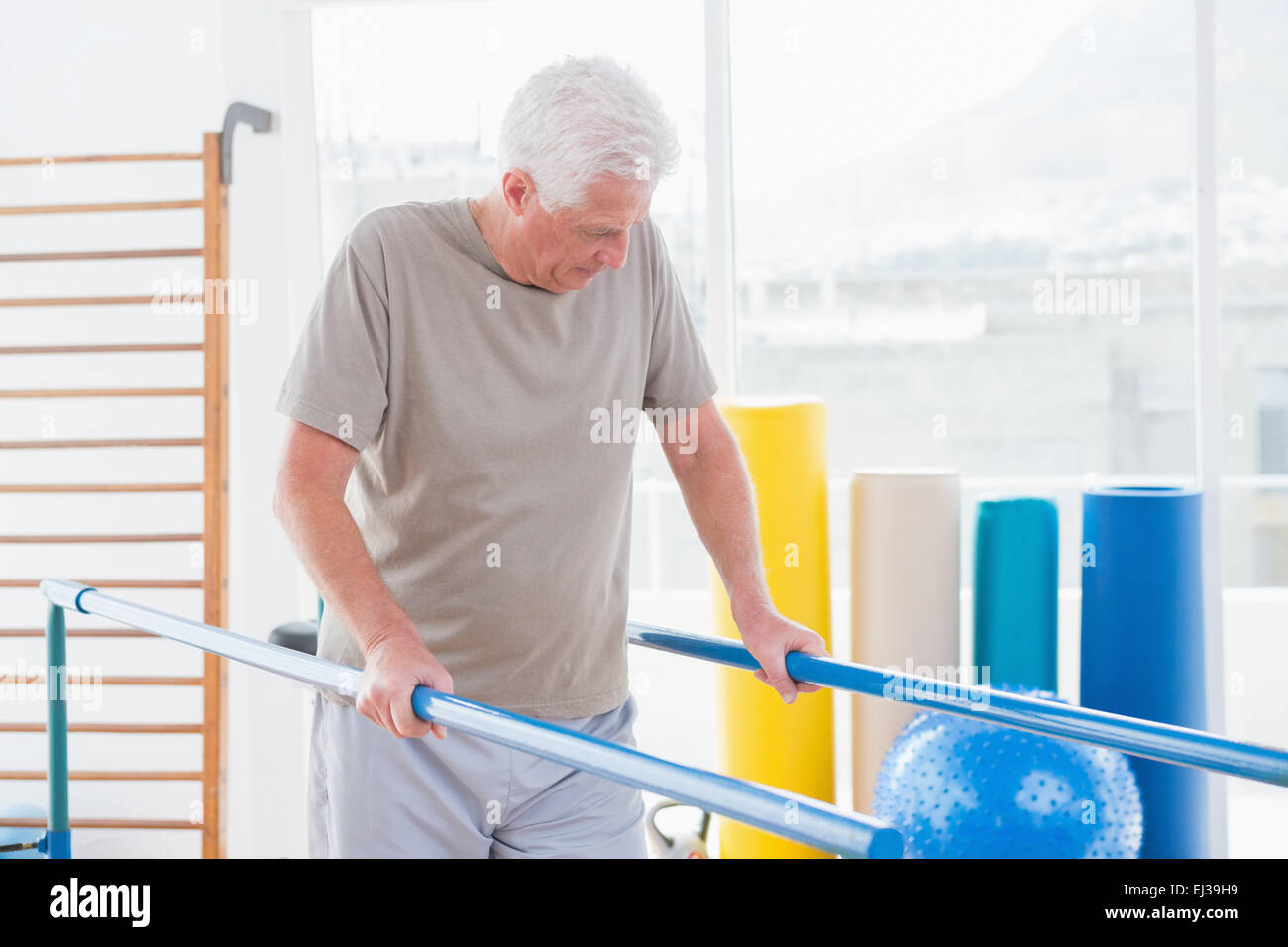 Senior man walking with parallel bars Stock Photo - Alamy