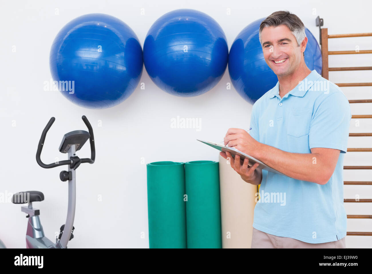 Smiling trainer writing on clipboard Stock Photo - Alamy
