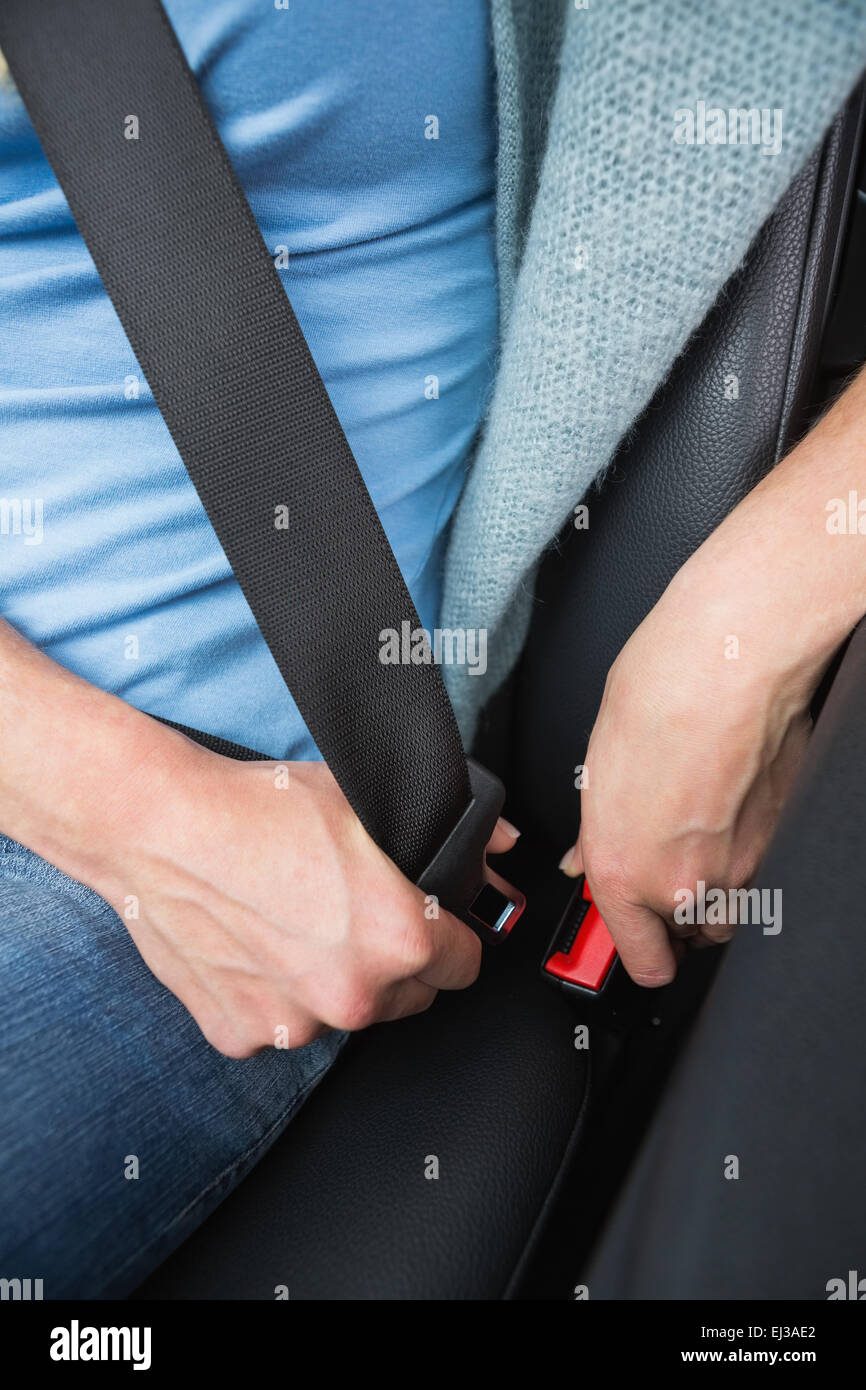 Woman putting on her seat belt Stock Photo - Alamy
