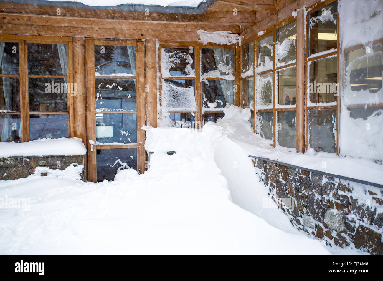 Classic Austrian wooden house with big windows covered by snow at ...