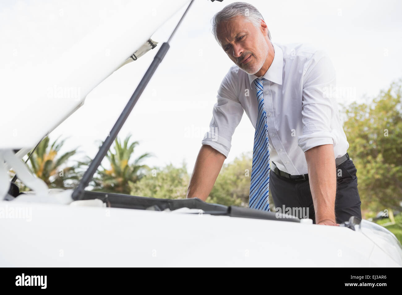 Upset man checking his car engine after breaking down Stock Photo - Alamy