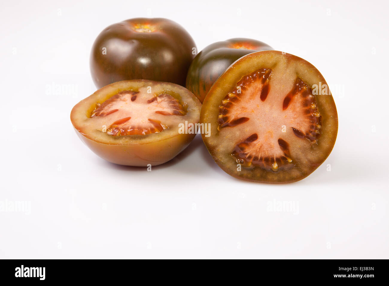 Dark green kumato tomatoes, whole and sliced. Isolated over white ...