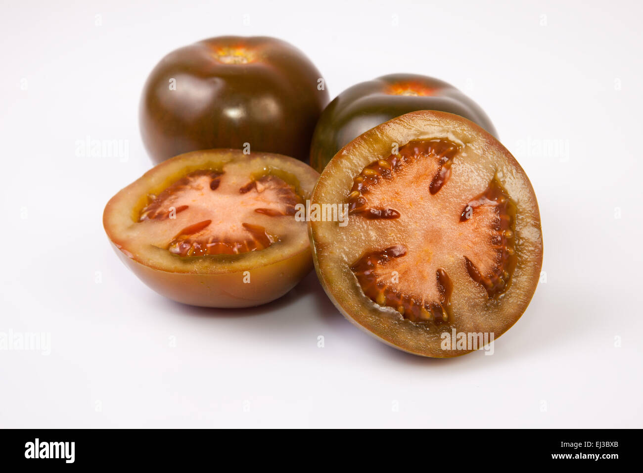 Dark green kumato tomatoes, whole and sliced. Isolated over white ...