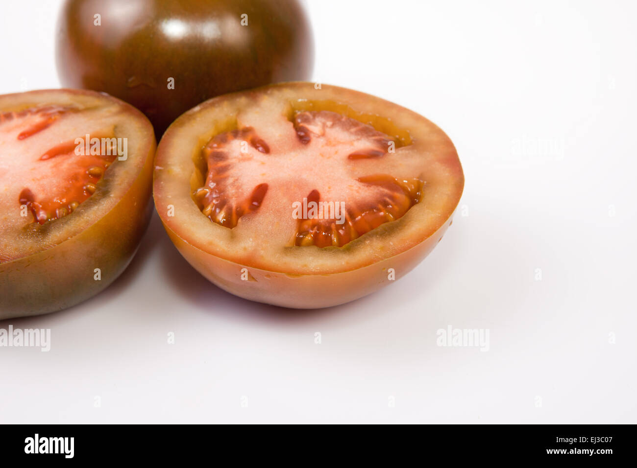 Dark green kumato tomatoes, whole and sliced. Isolated over white ...