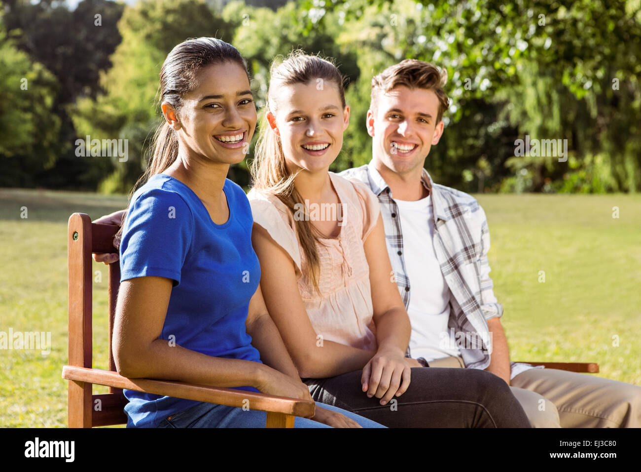 Happy friends sitting on bench Stock Photo - Alamy
