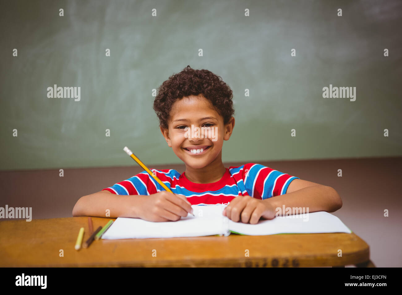 Little boy writing book in classroom Stock Photo - Alamy