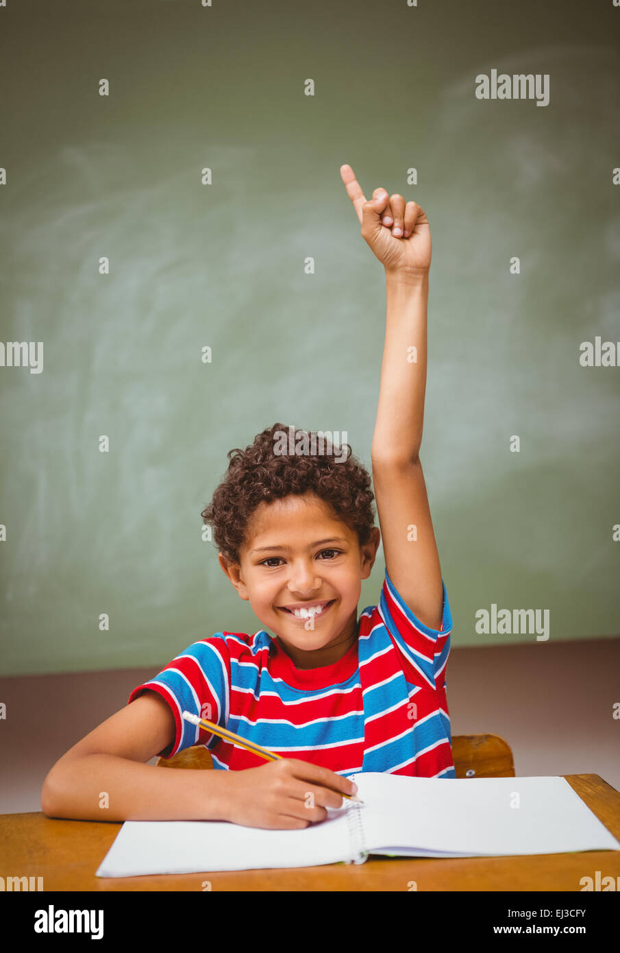 Little boy raising hand in classroom Stock Photo - Alamy
